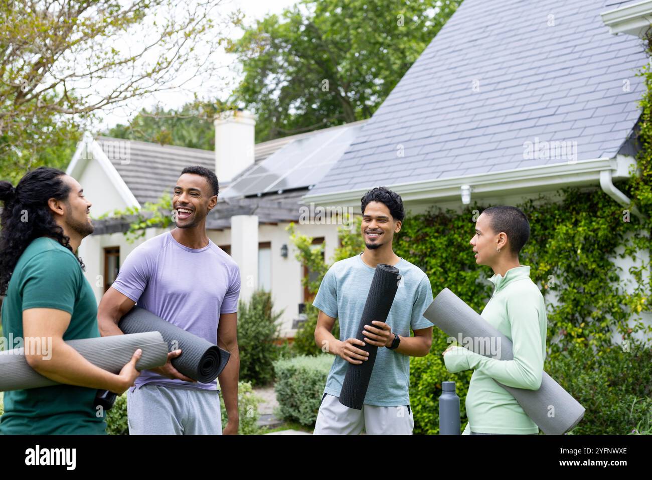 Young multiracial friends laughing and holding yoga mats outside house ...
