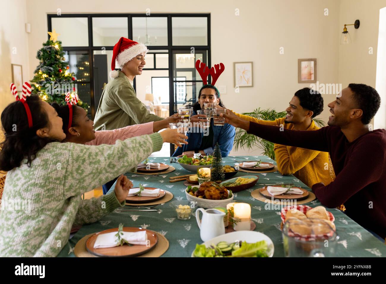 multiracial friends celebrating Christmas dinner at home, toasting with ...