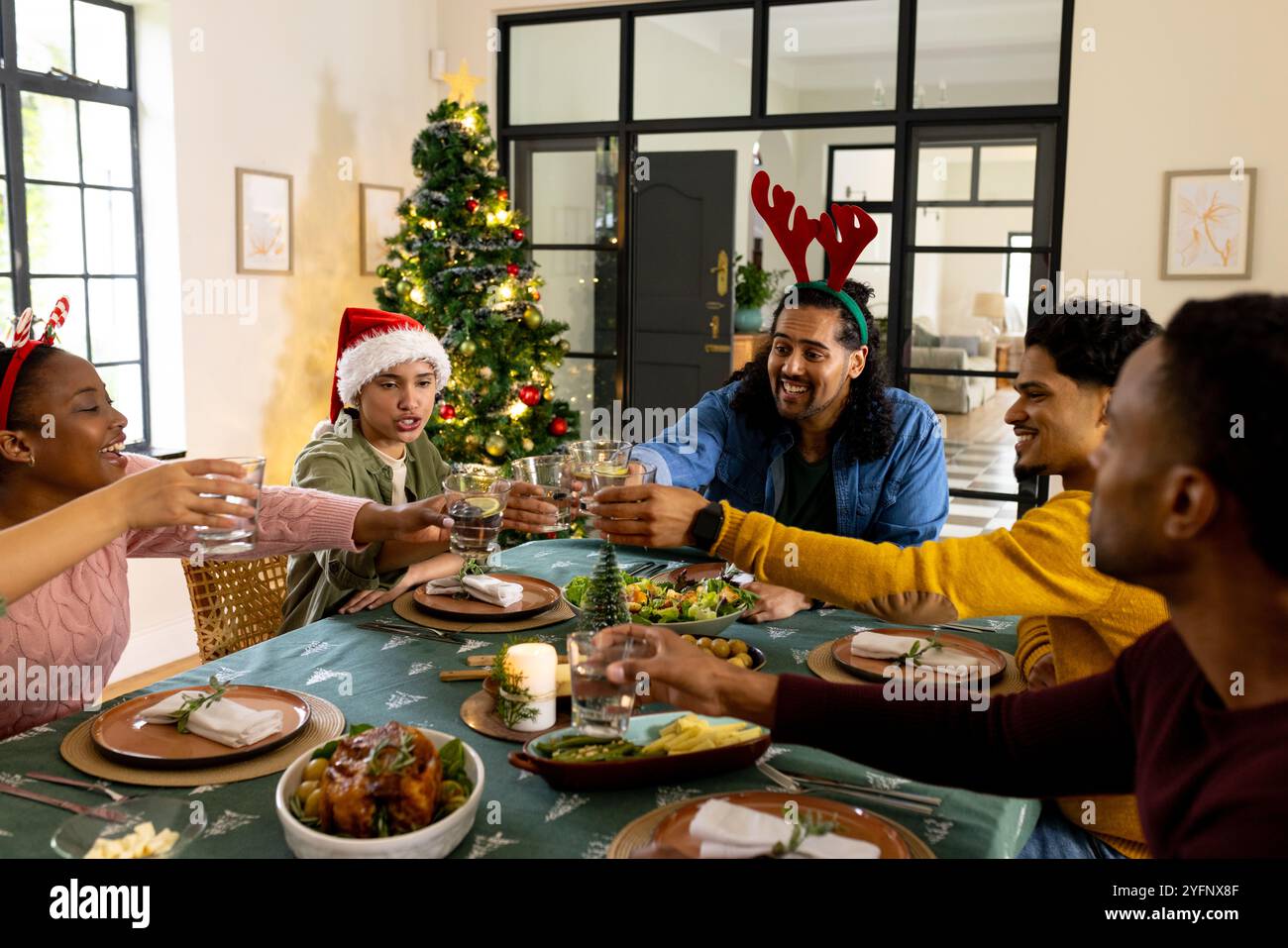 multiracial friends celebrating Christmas at home, toasting around ...