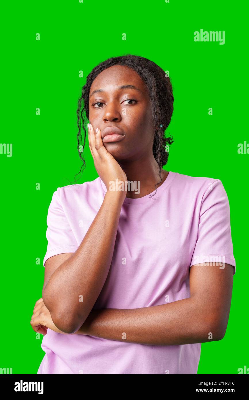 Young woman with an expression of contemplation poses against a bright ...