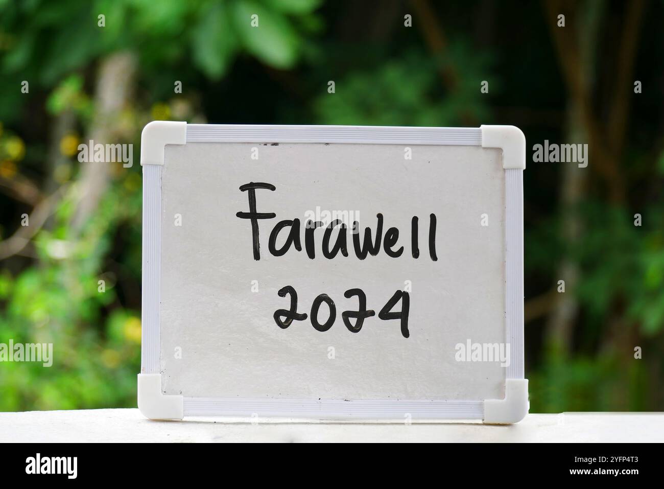 handwritten text "Farewell 2024" on white chalkboard with blurred ...