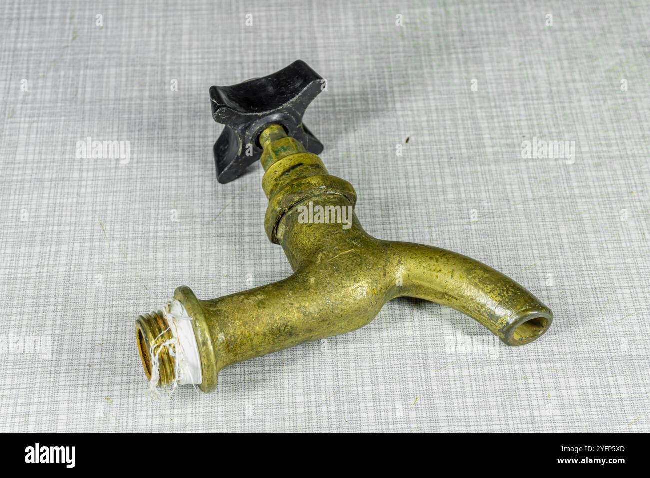 An old bronze water tap with a plastic valve with remains of silicone ...