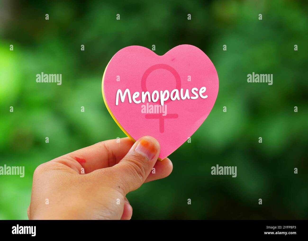 Hand holding a heart shaped paper sign with the writing Menopause on a ...