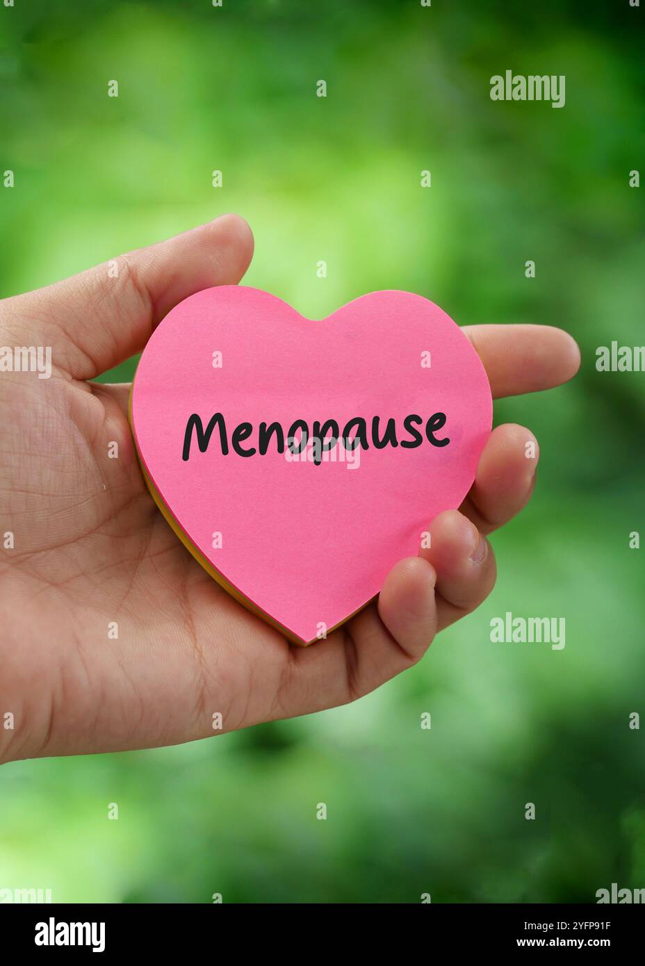 Hand holding a heart shaped paper sign with the writing Menopause on a ...