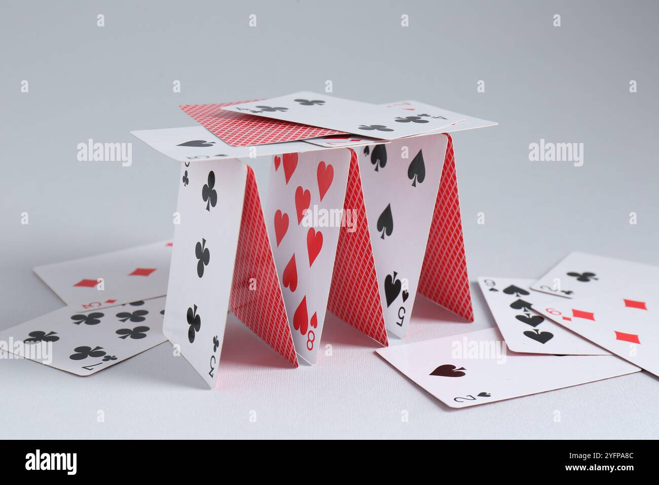 Collapsed house of playing cards on light grey background, closeup ...