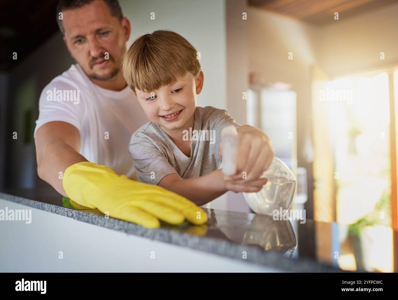 Father, child and cleaning table with spray in home for helping hand ...