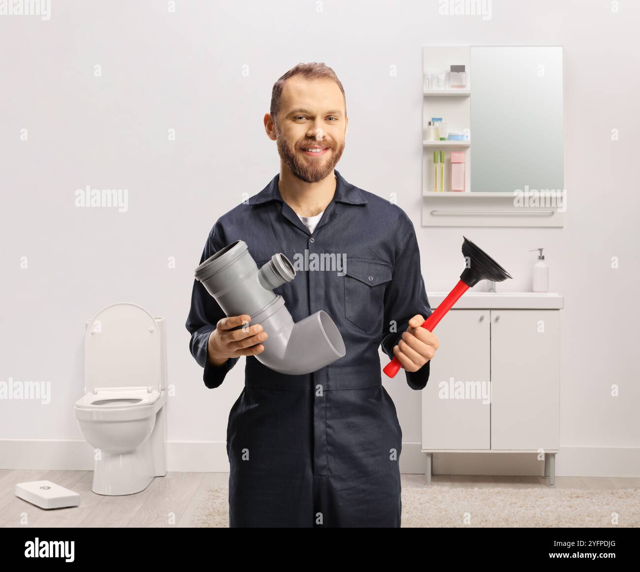 Plumber holding a pipe and a toilet plunger in a bathroom Stock Photo ...