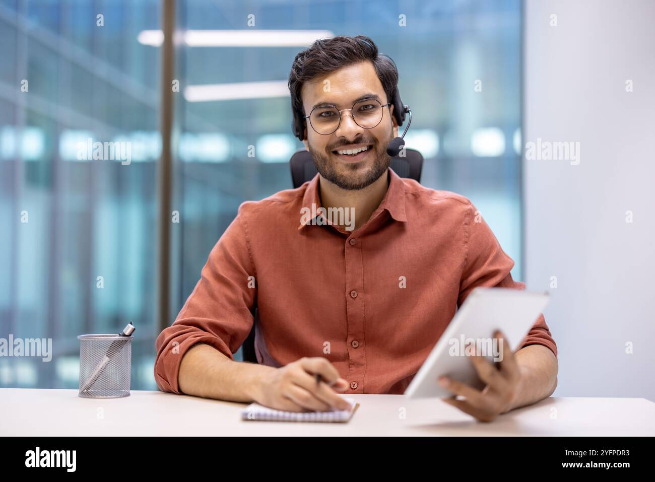Hispanic businessman with headset in office, holding tablet, smiling ...