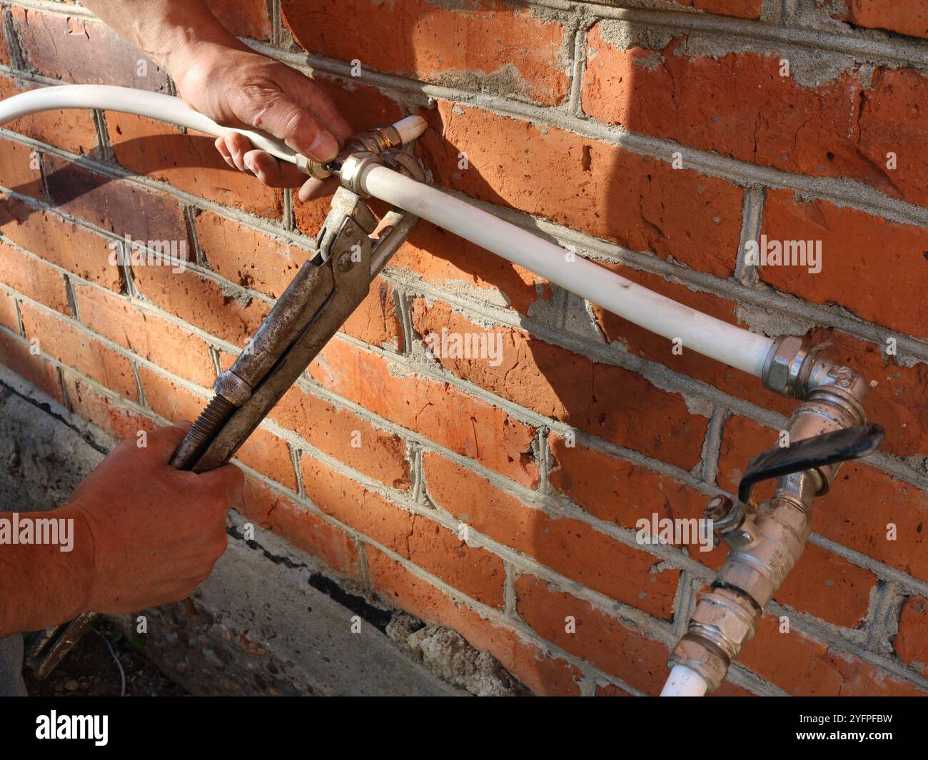 Adjustable pipe wrench in a man's hand during the process of working on ...