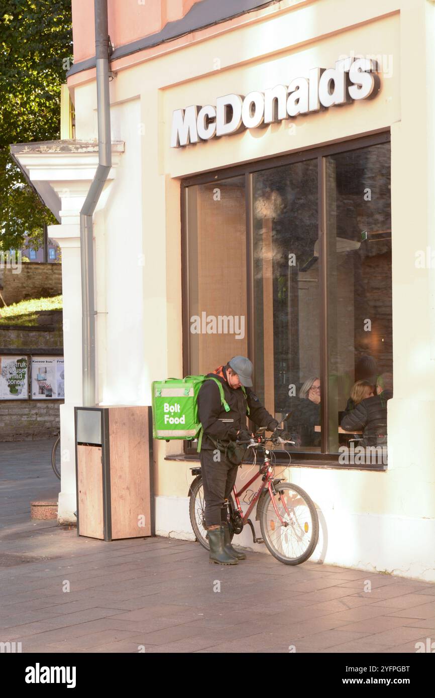 A Bolt Food delivery rider on a bicycle outside a McDonalds fast-food ...
