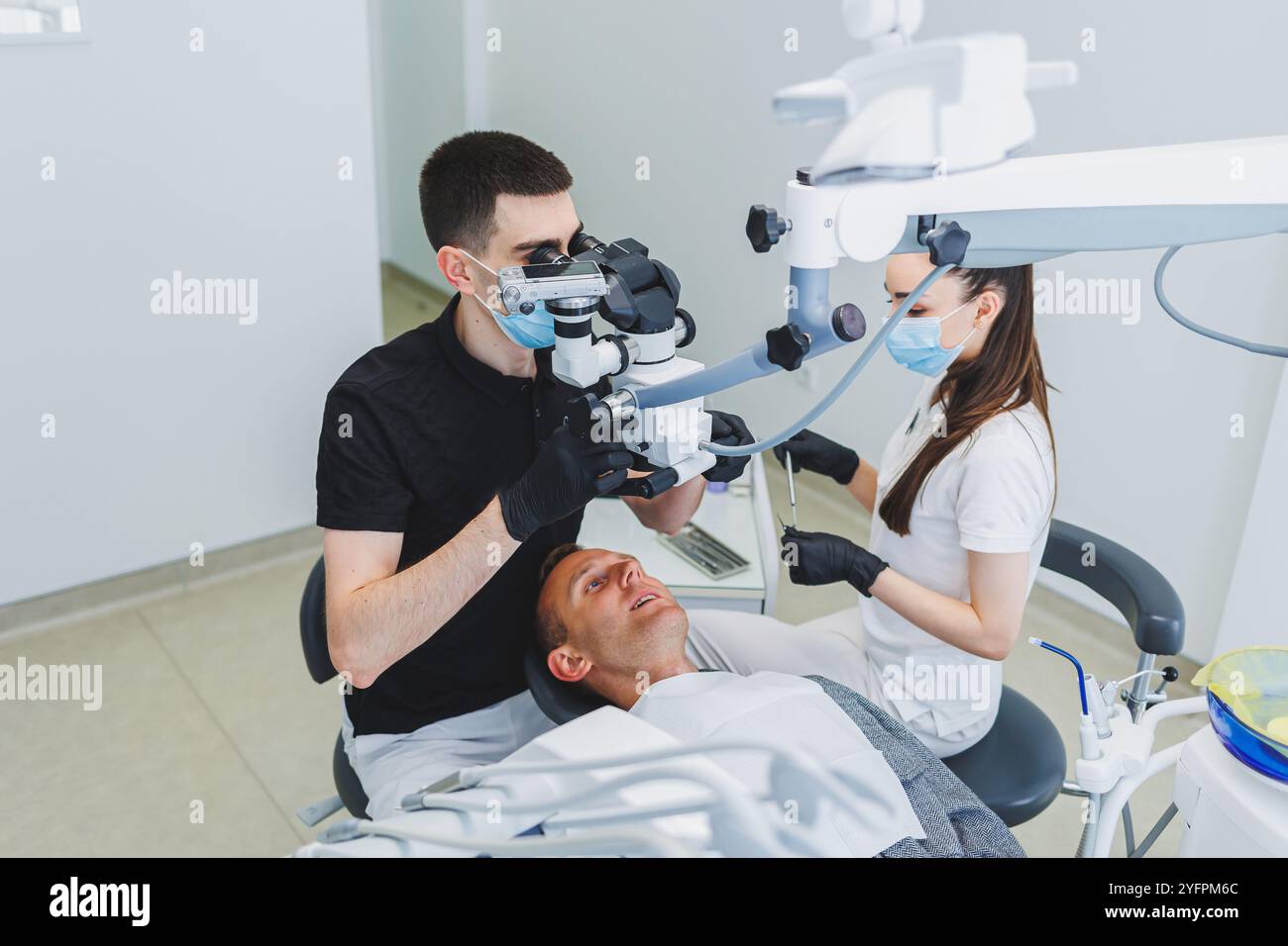 Modern dental office with a microscope. A dentist treats a man's teeth ...