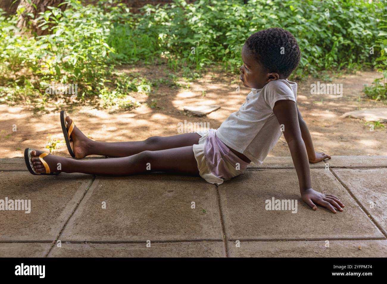 portrait of african girl resting laying flat on the ground , garden in ...
