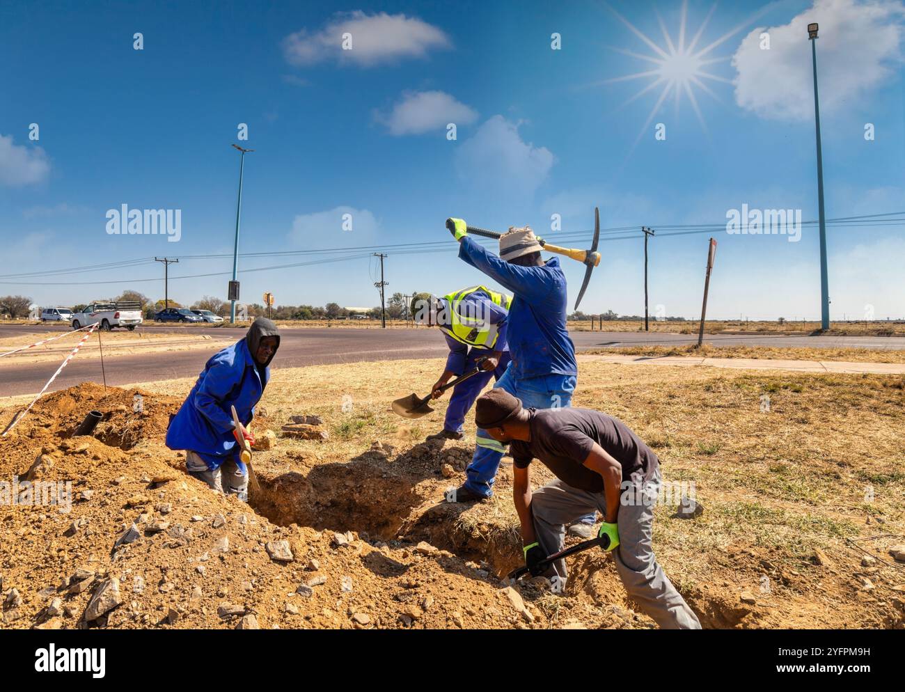 group of African workers digging a trench on the side of the highway ...