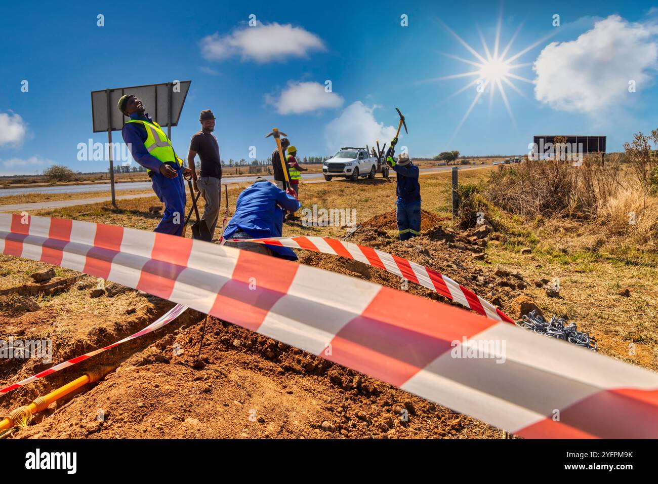 team of african construction workers in a trench ditch repairing fixing ...