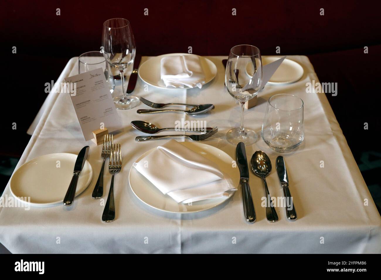 Elegant table setting in the restaurant. Several types of glass, plates ...