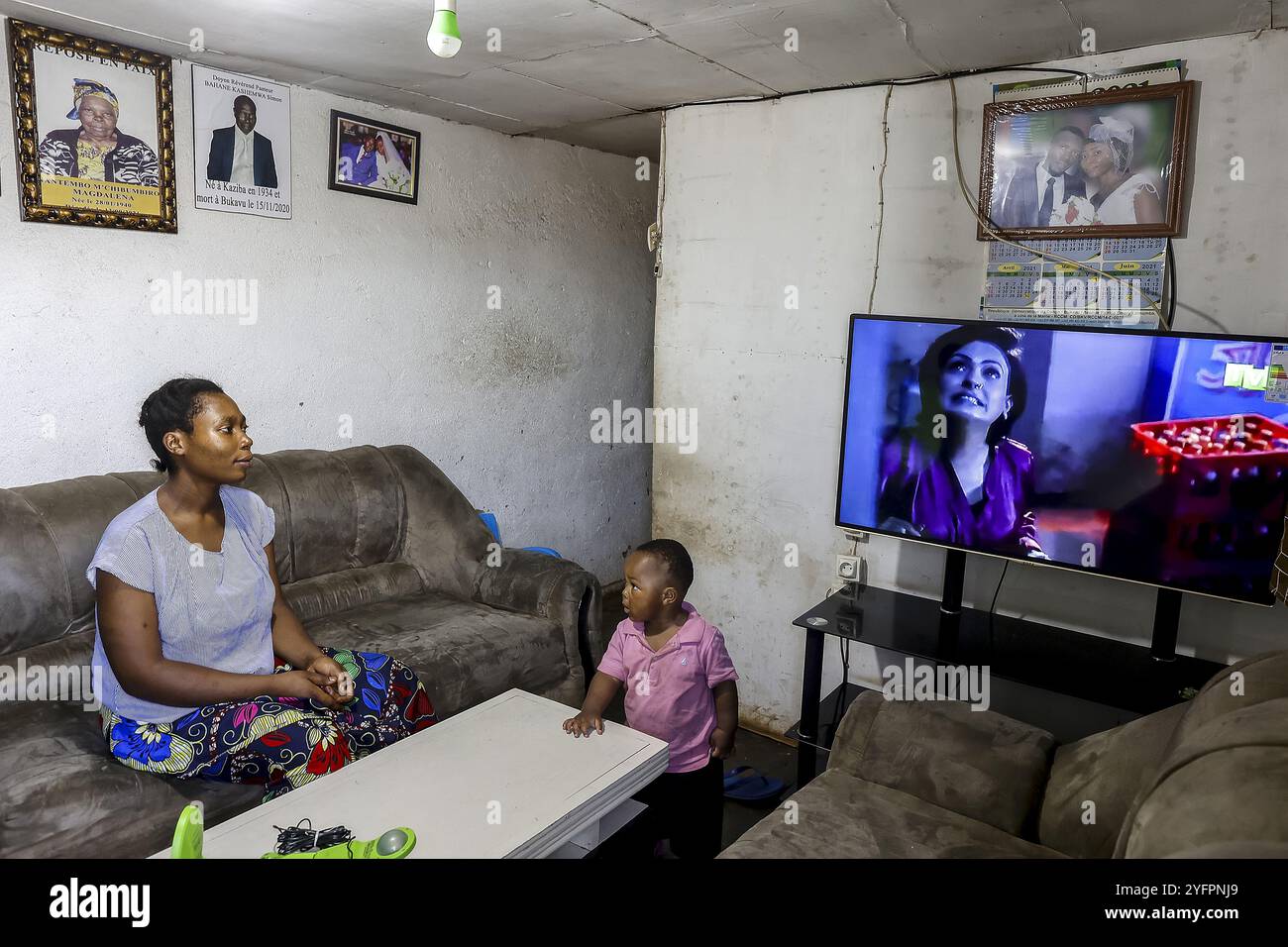 Mother watching solar-powered TV in her home in Bukavu, DRC Stock Photo - Alamy