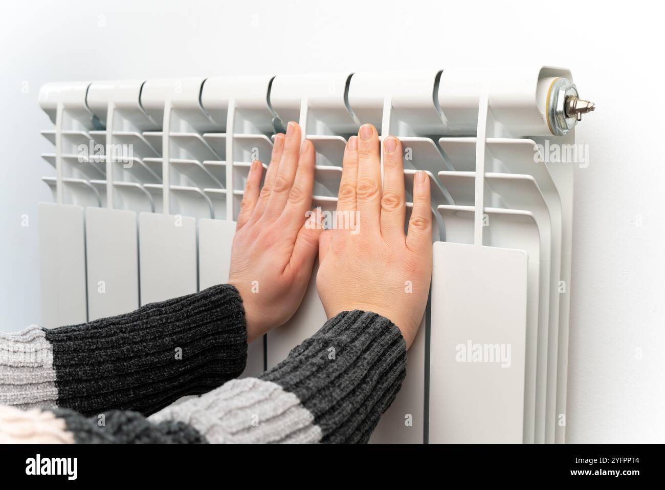 Close up of woman hands heating touching central radiator thermostat ...