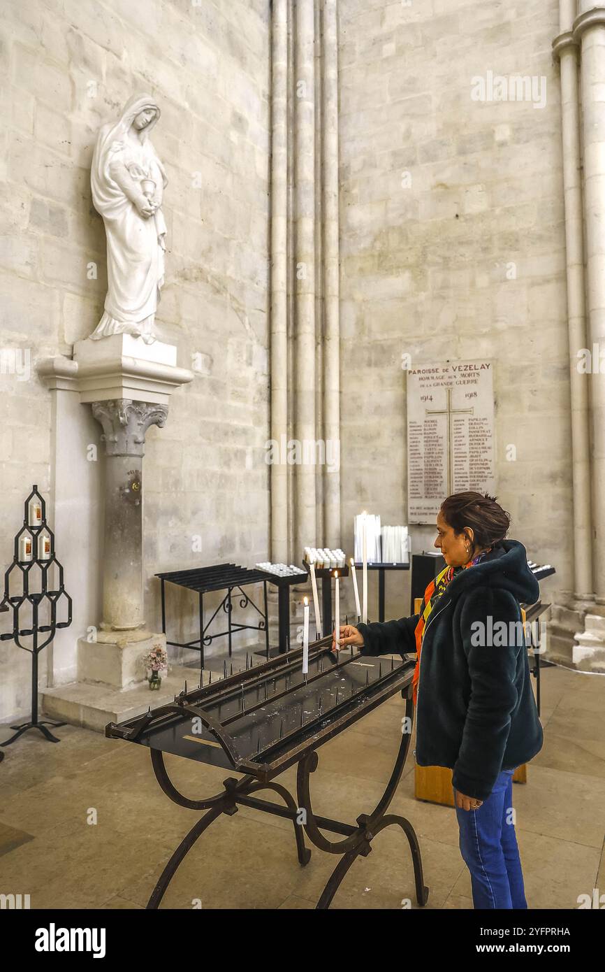 Woman lighting a candle in Vezelay abbey, in French Sainte-Marie ...
