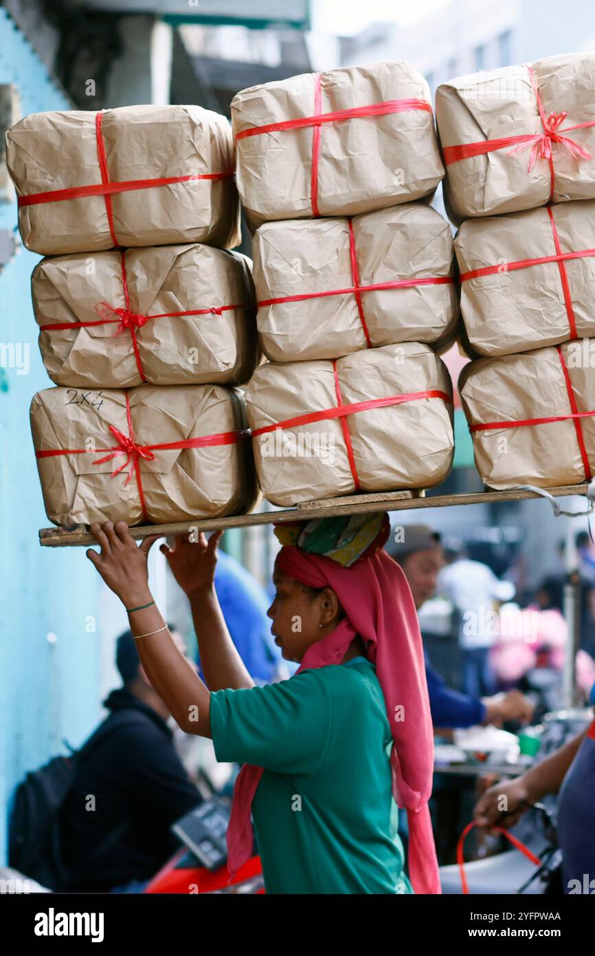 Daily worker at traditional food market. Woman carrying heavy bags with ...