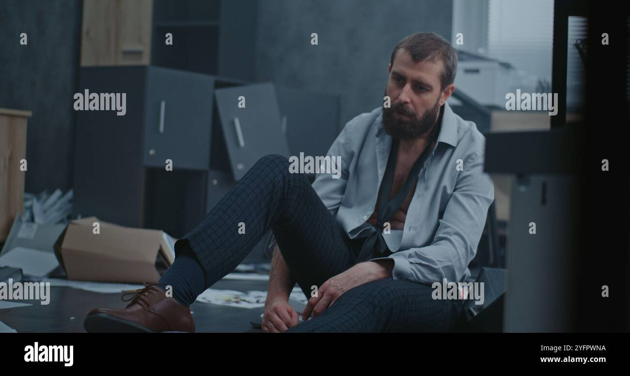 Frustrated office worker sits on the floor, breathes heavily after ...