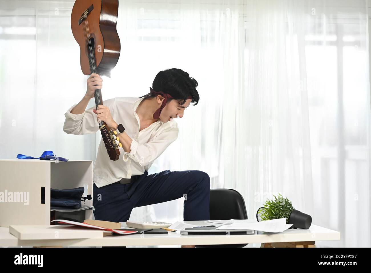 Angry male employee smashing guitar on his office desk Stock Photo - Alamy