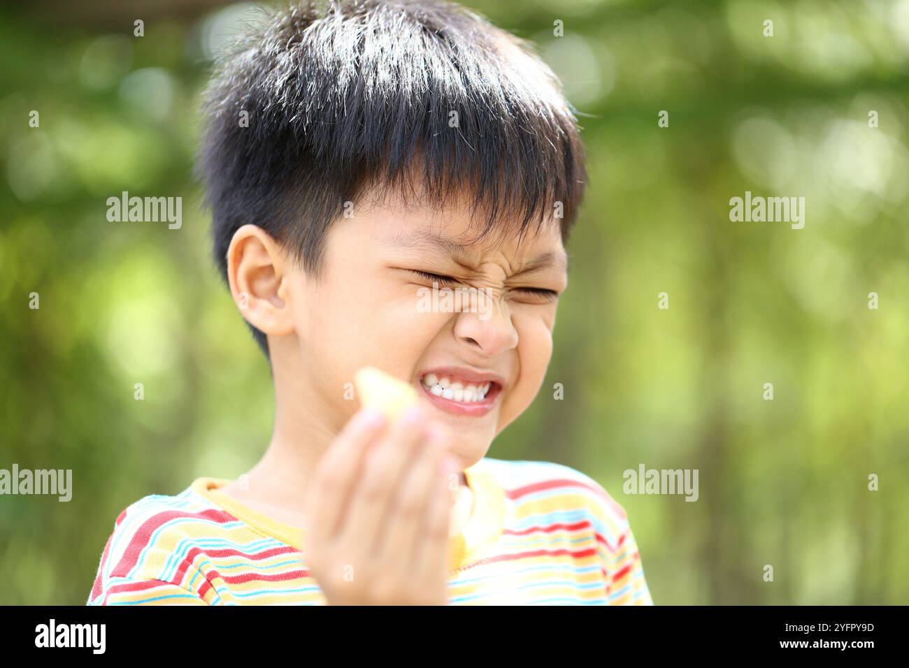 A cheerful boy smiles with delight while enjoying a slice of fruit ...