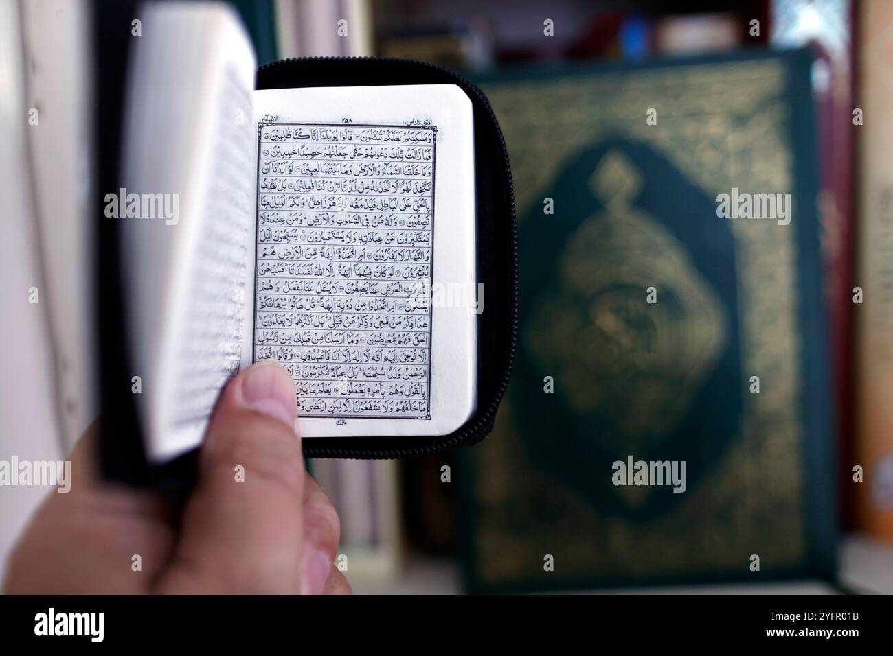 Muslim man reading a mini holy Quran in arabic. Close up on hand Stock ...
