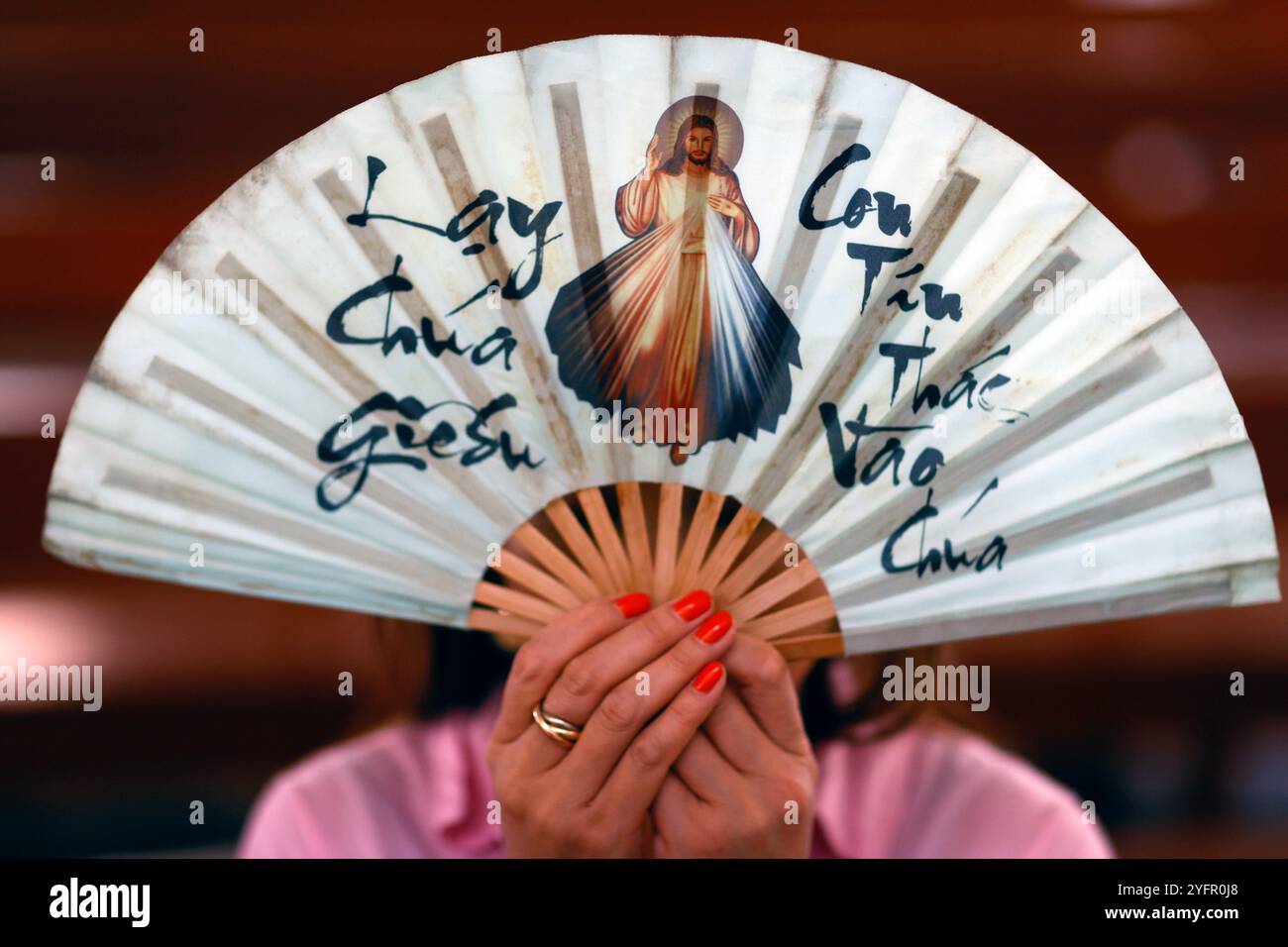 Catholic woman holding a Jesus Christ fan Stock Photo - Alamy