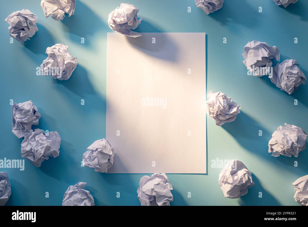 Crumpled paper surrounds an empty sheet on a blue background in a ...