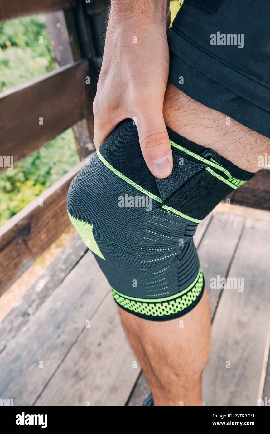 Athlete with a knee bandage during outdoor fitness activity, showcasing ...