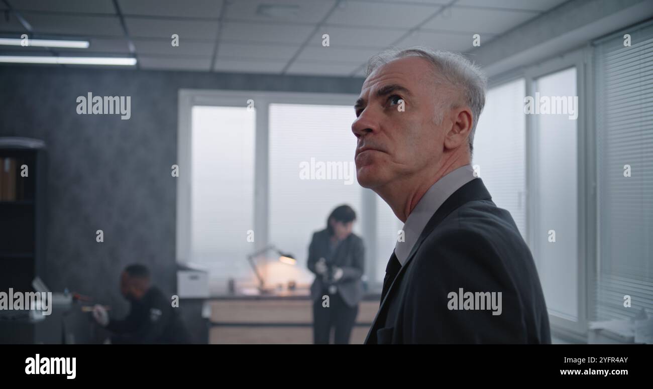 Office robbery case: Medium close up of male detective examining crime ...