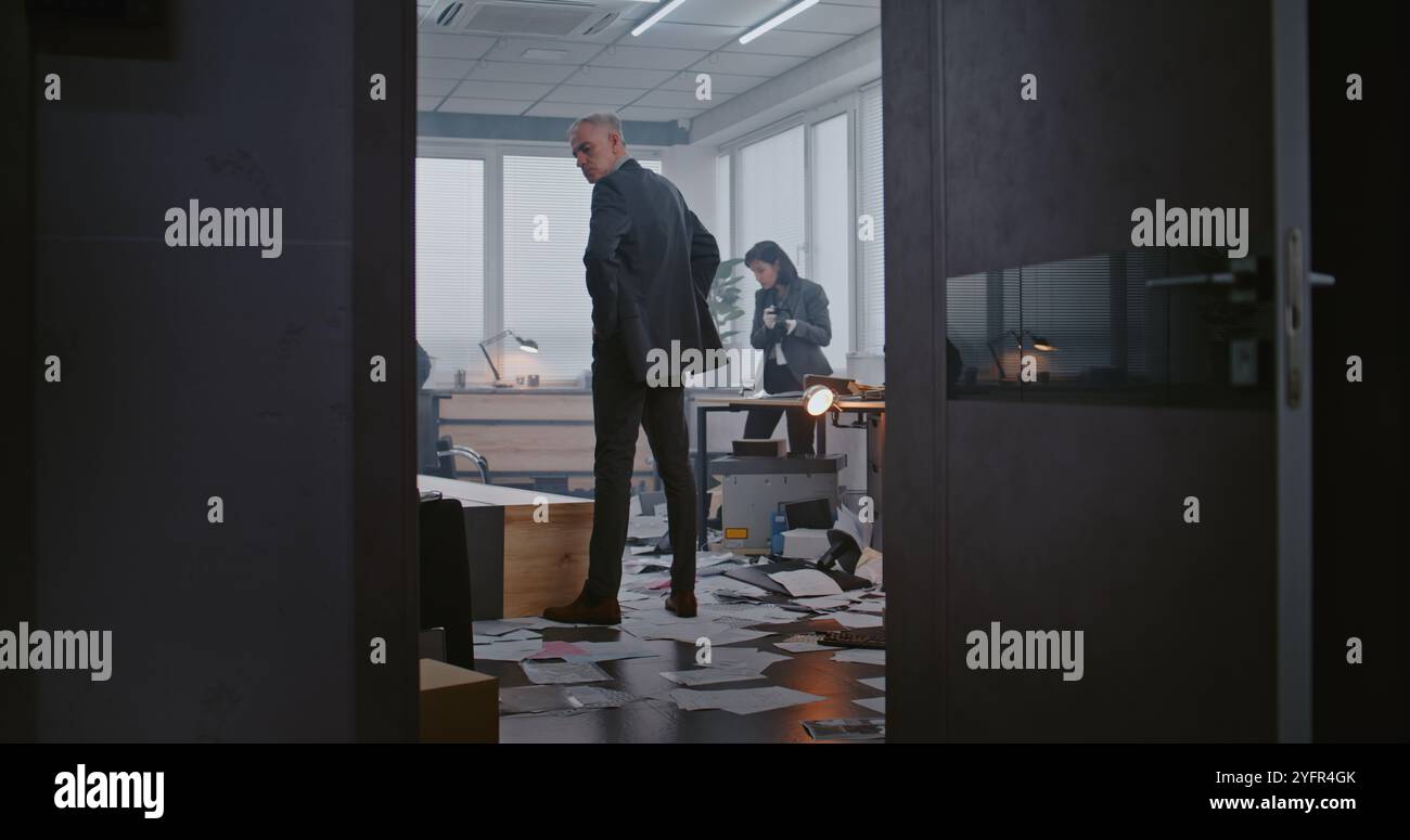 Robbery case in office room: Male detective in suit examines crime ...