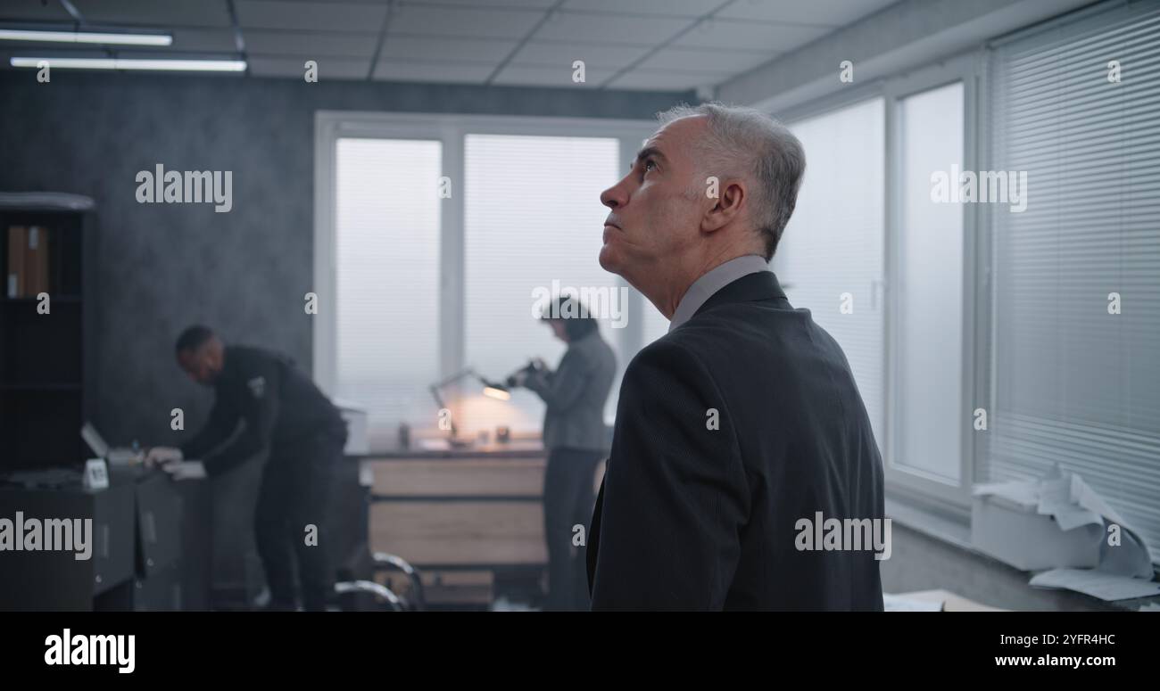 Office robbery case: Medium close up of male detective examining crime ...