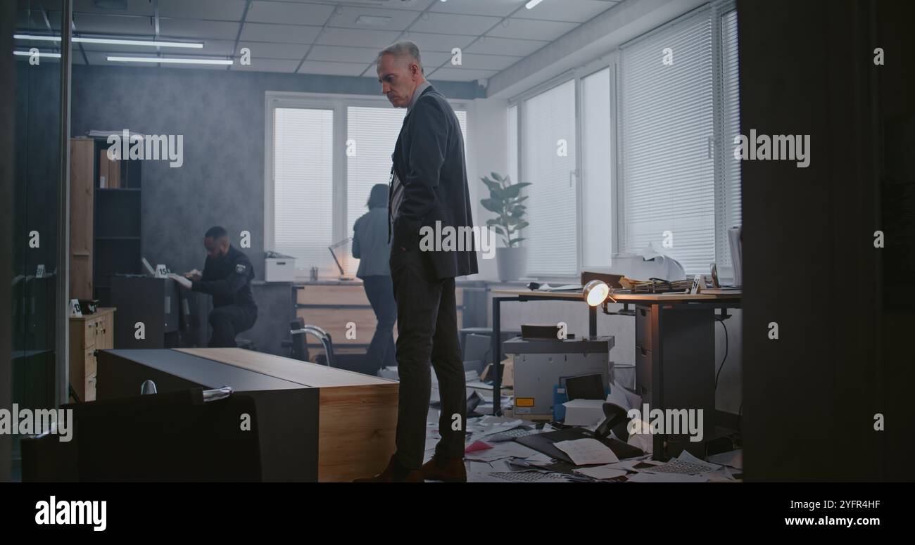 Robbery case in office room: Male detective in suit examines crime ...