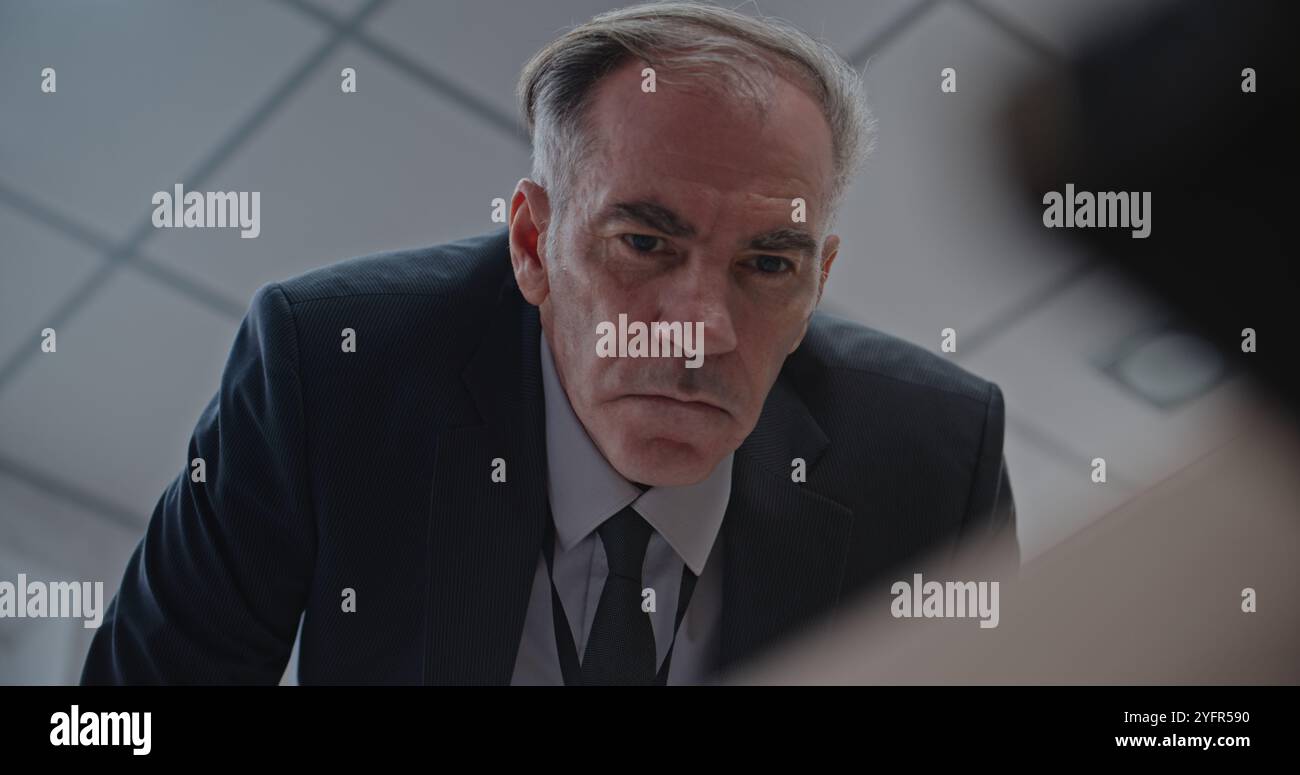 Low angle close up of serious male detective in suit looking at the ...