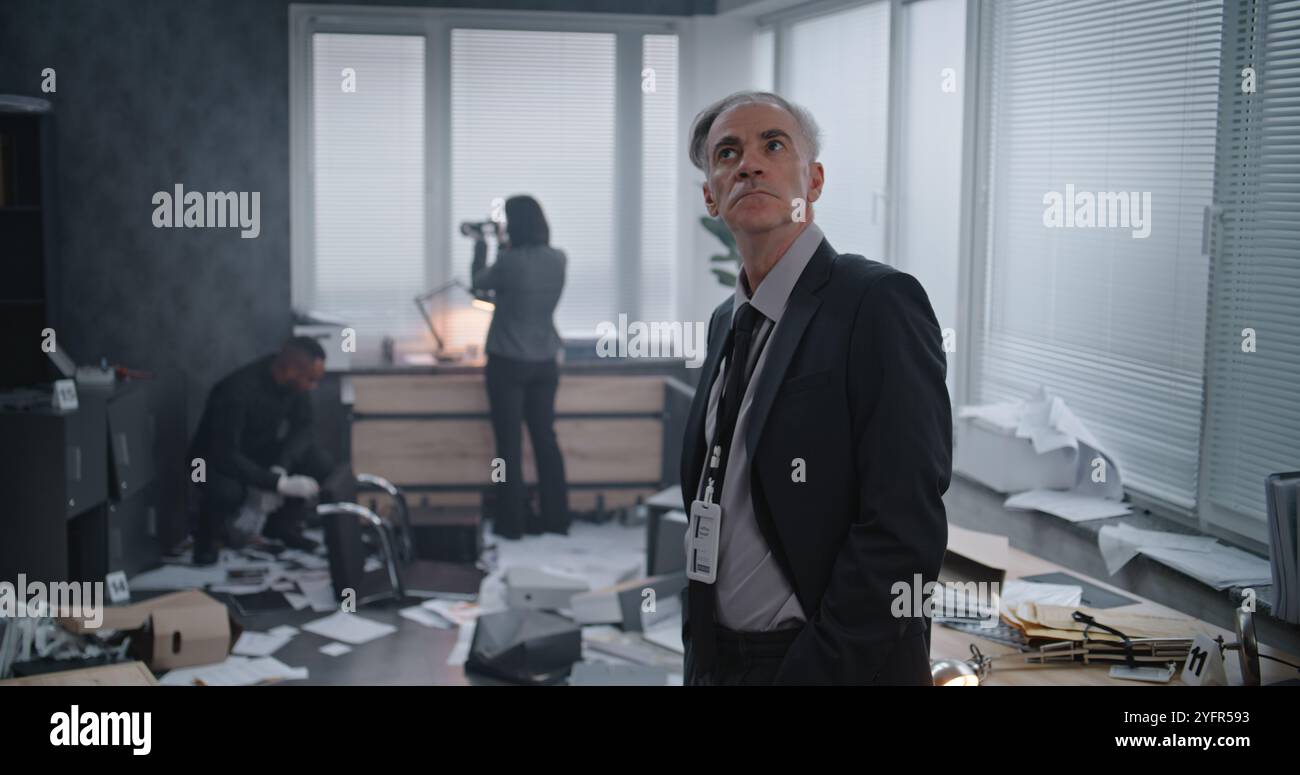 Office robbery case: Medium close up of male detective examining crime ...