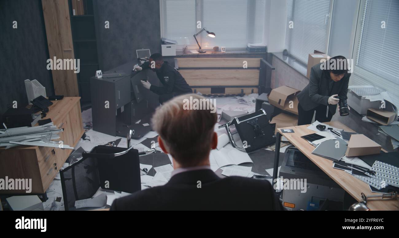 Office robbery case: Back view of male detective in suit examining ...