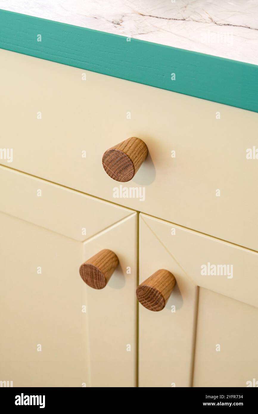 Wooden handles attached to yellow sleek kitchen cabinets with a simple ...