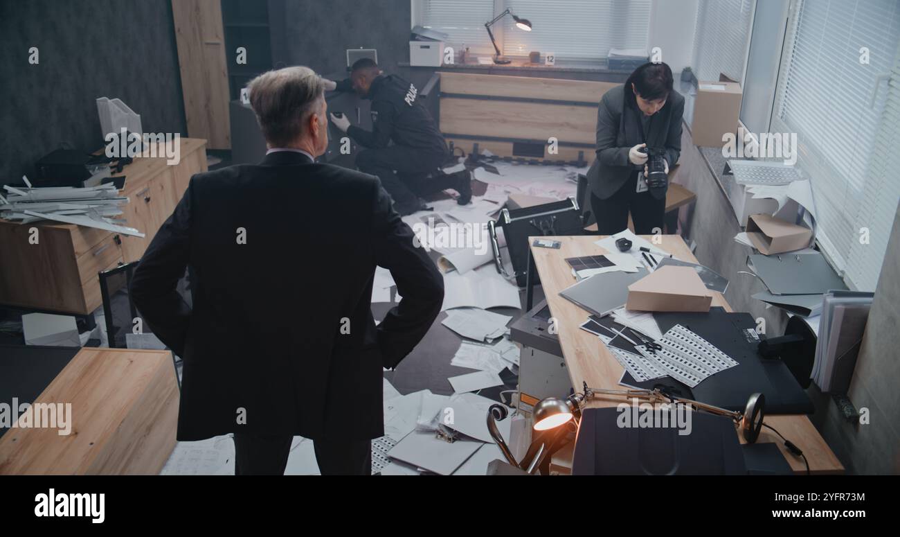 Office robbery case: High angle of detective examining crime scene ...
