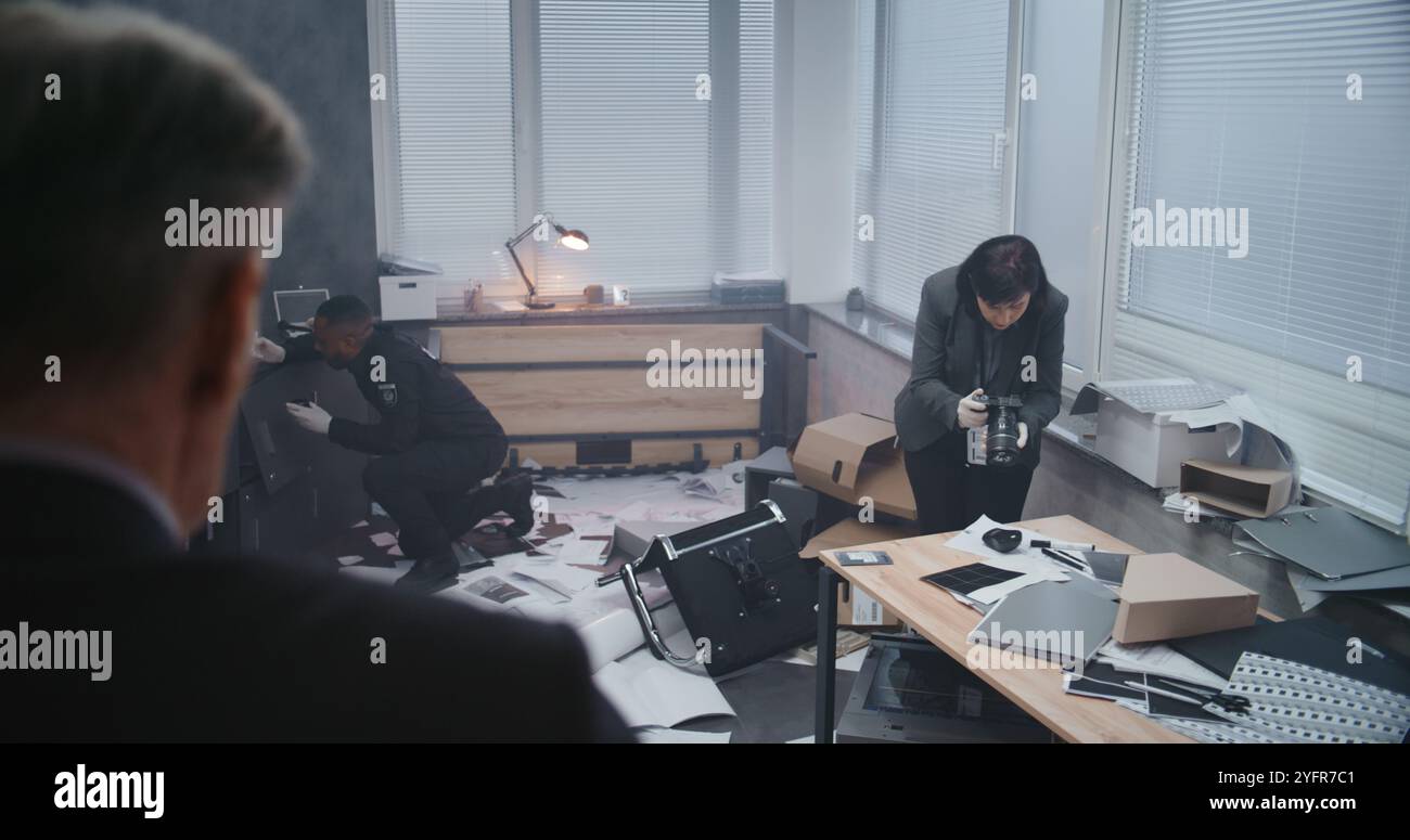 Office robbery case: Back view of detective examining crime scene ...