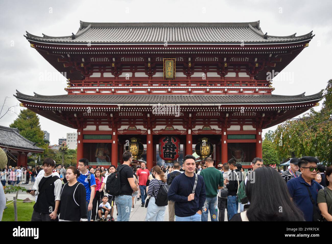 Crowd gathers in front of the iconic temple in Tokyo, Japan during a cloudy day, showcasing ...