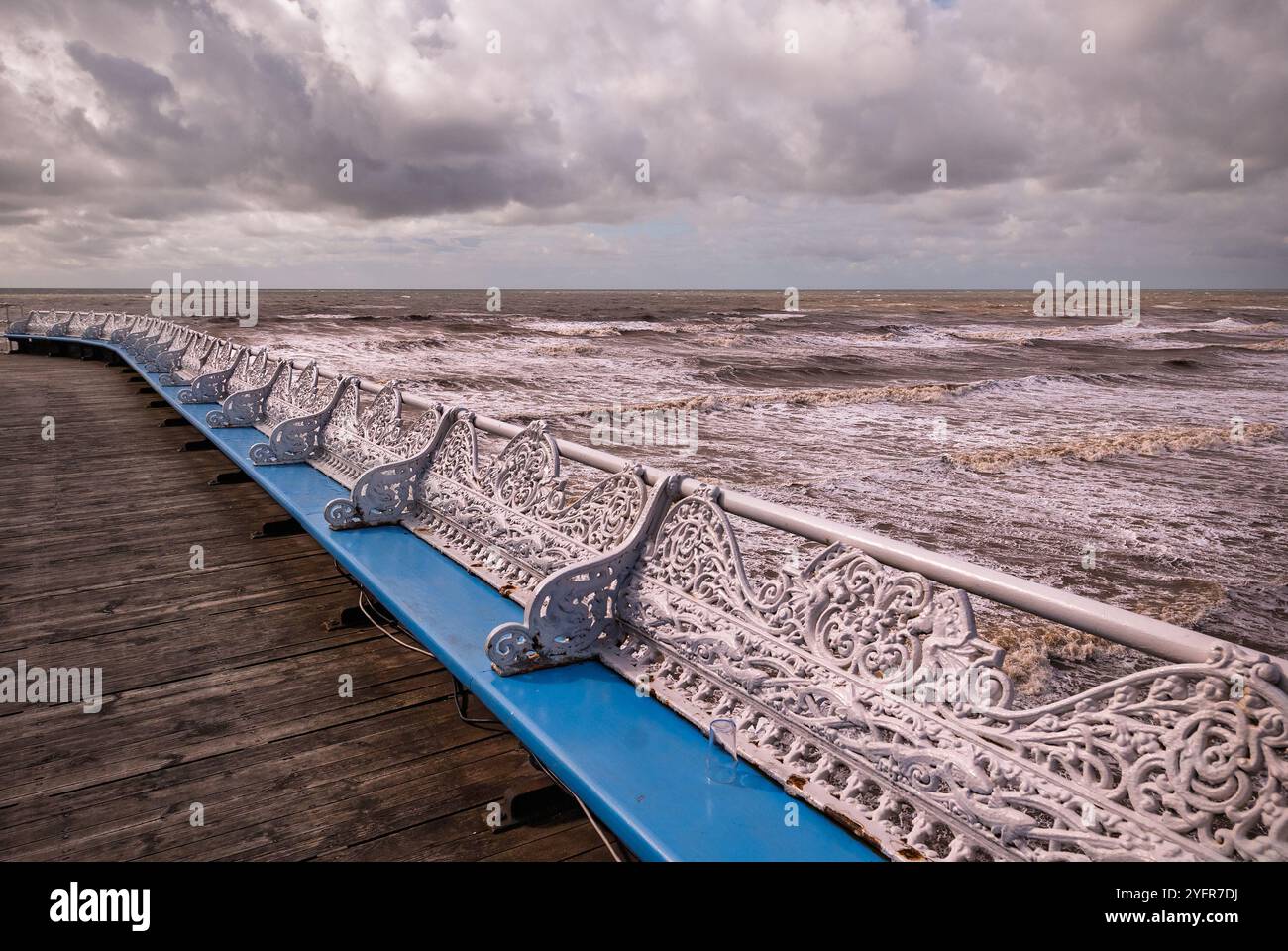 Wrought iron seating on Blackpool pier with large waves Stock Photo - Alamy