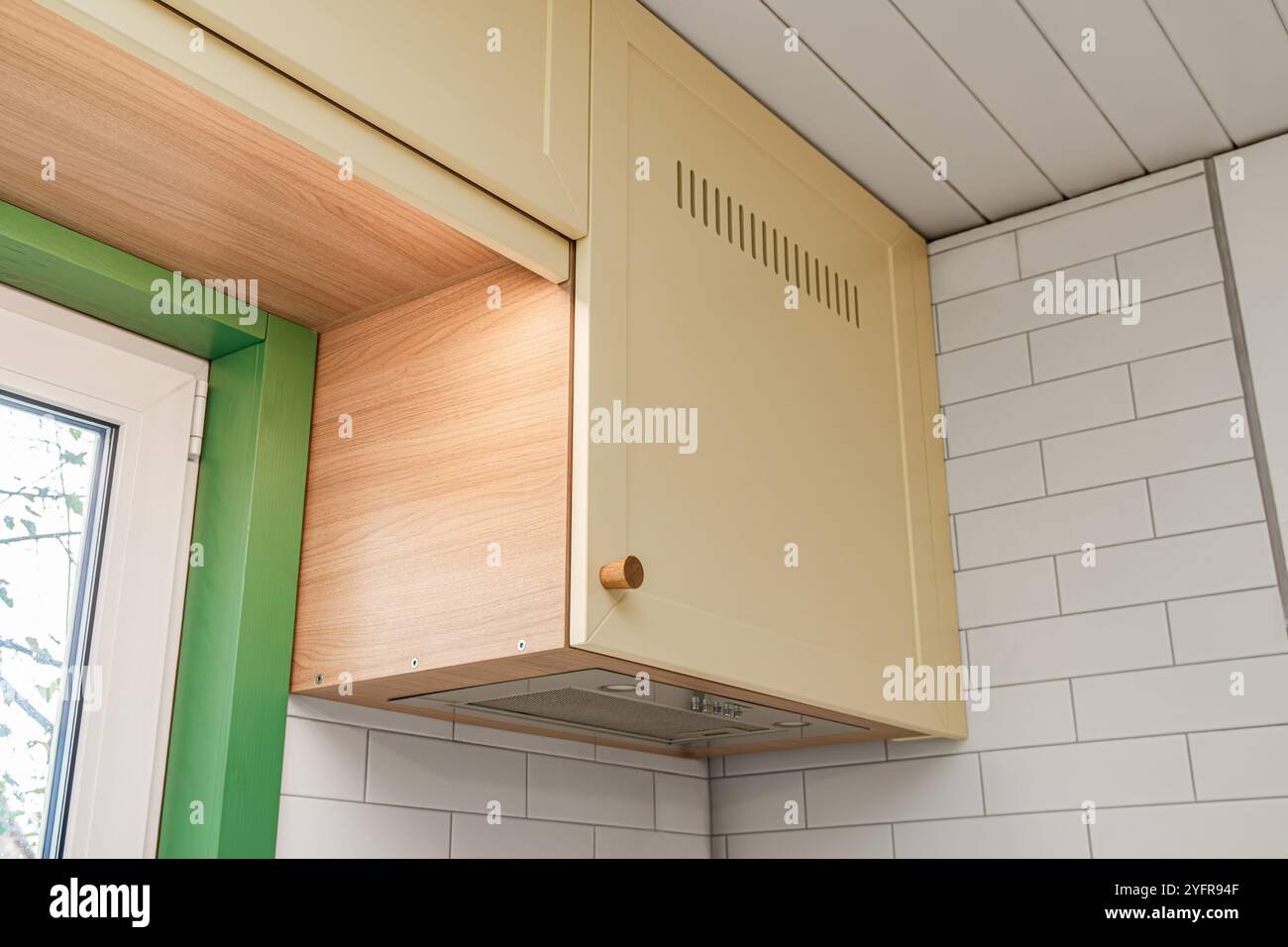 Fragment of upper kitchen cabinets with yellow facades and wooden knobs ...