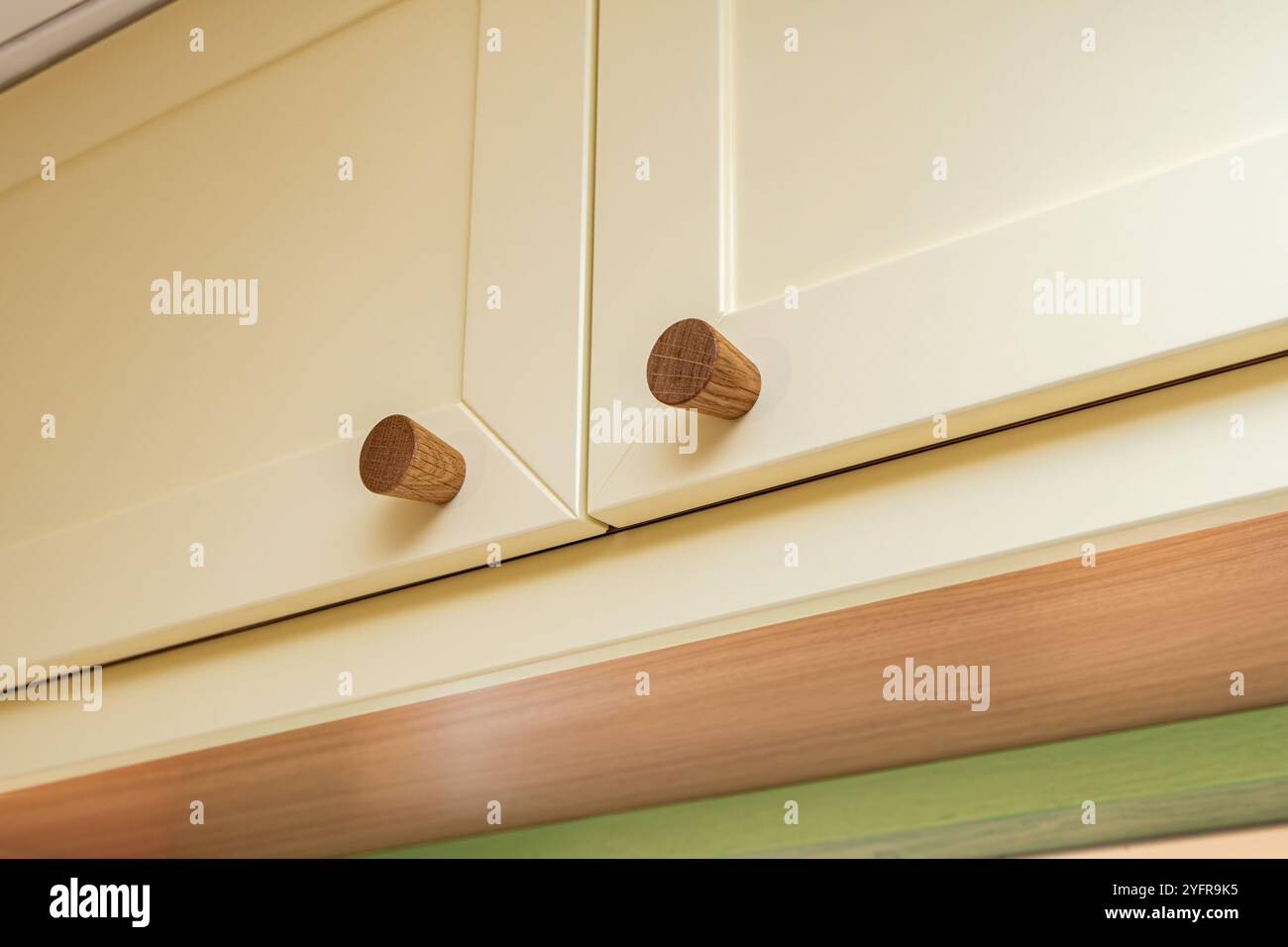 Wooden handles attached to yellow sleek kitchen cabinets with a simple ...