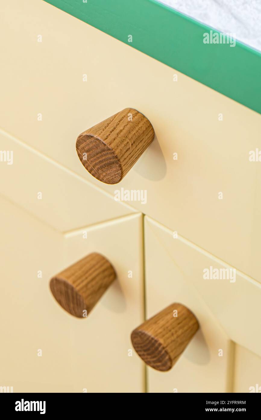 Wooden handles attached to yellow sleek kitchen cabinets with a simple ...