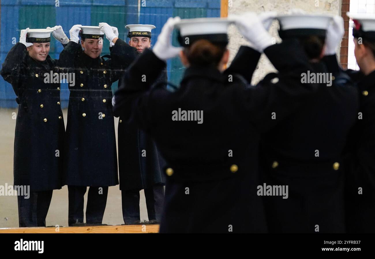 Royal Navy ratings use a mirror to adjust their uniforms before joining ...