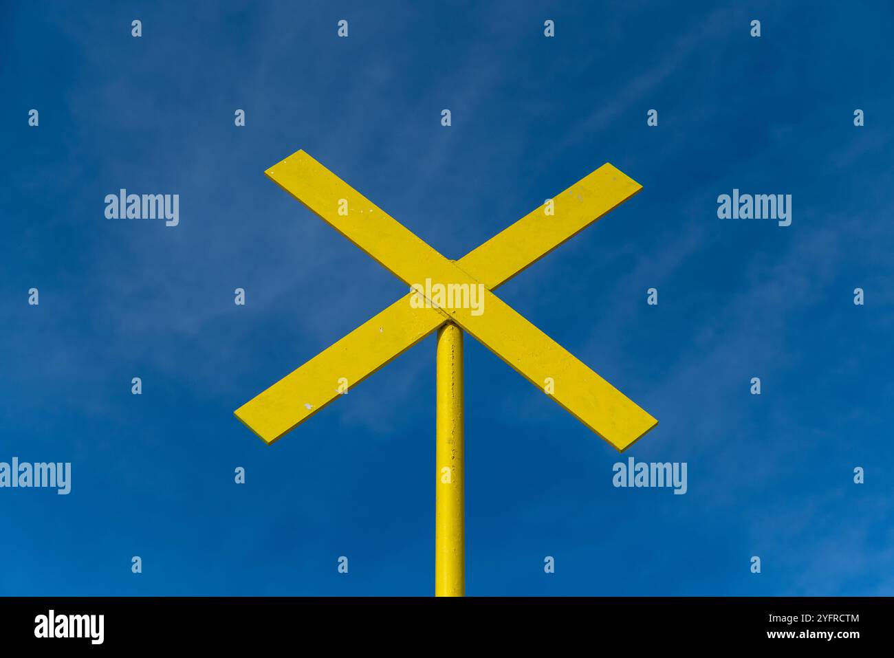 Bright yellow cross sign contrasting with a blue sky. Portsmouth, UK ...