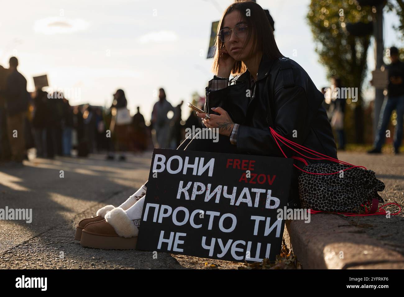 Ukrainian girl sitting with a poster "They Are Screaming, But You Don't ...