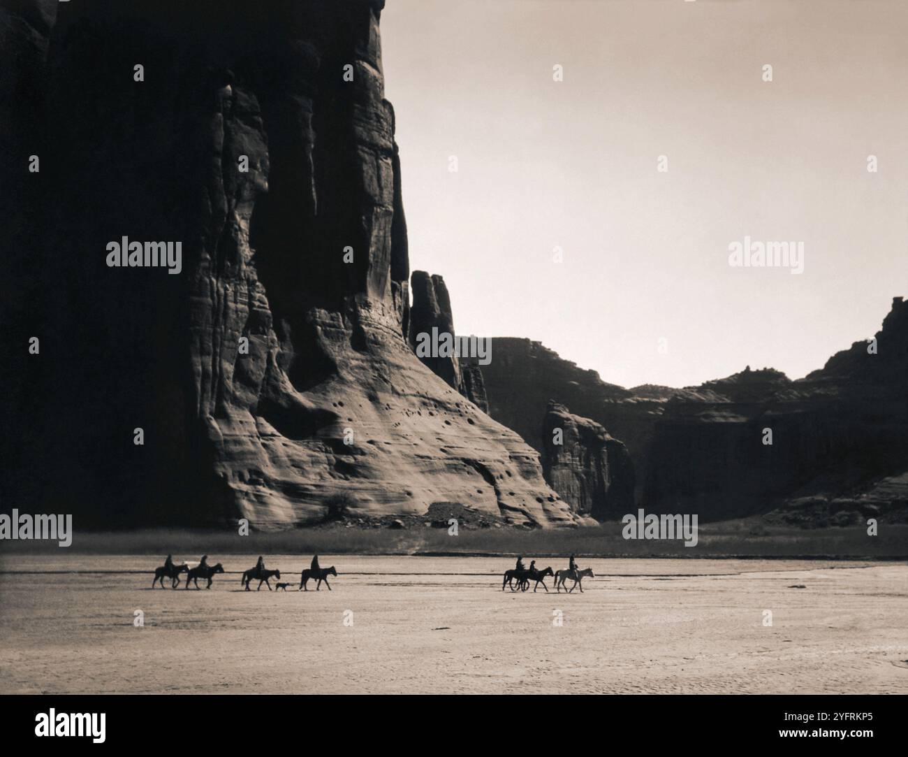 Seven Native Navajo riders on horseback and dog traveling against a ...