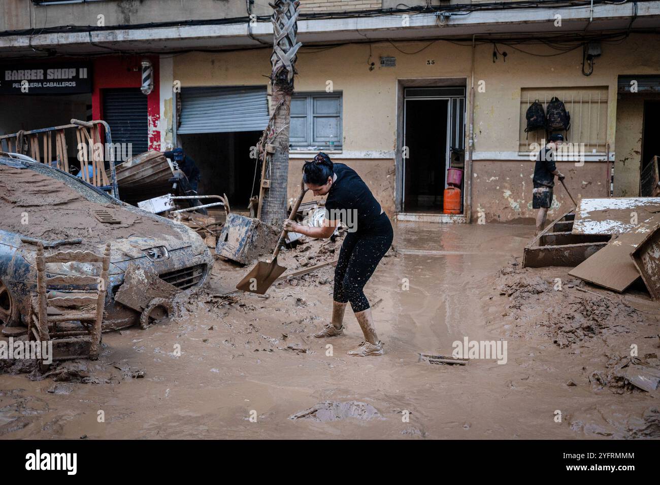 A woman cleaning out the street from mud. A recent DANA (Isolated ...